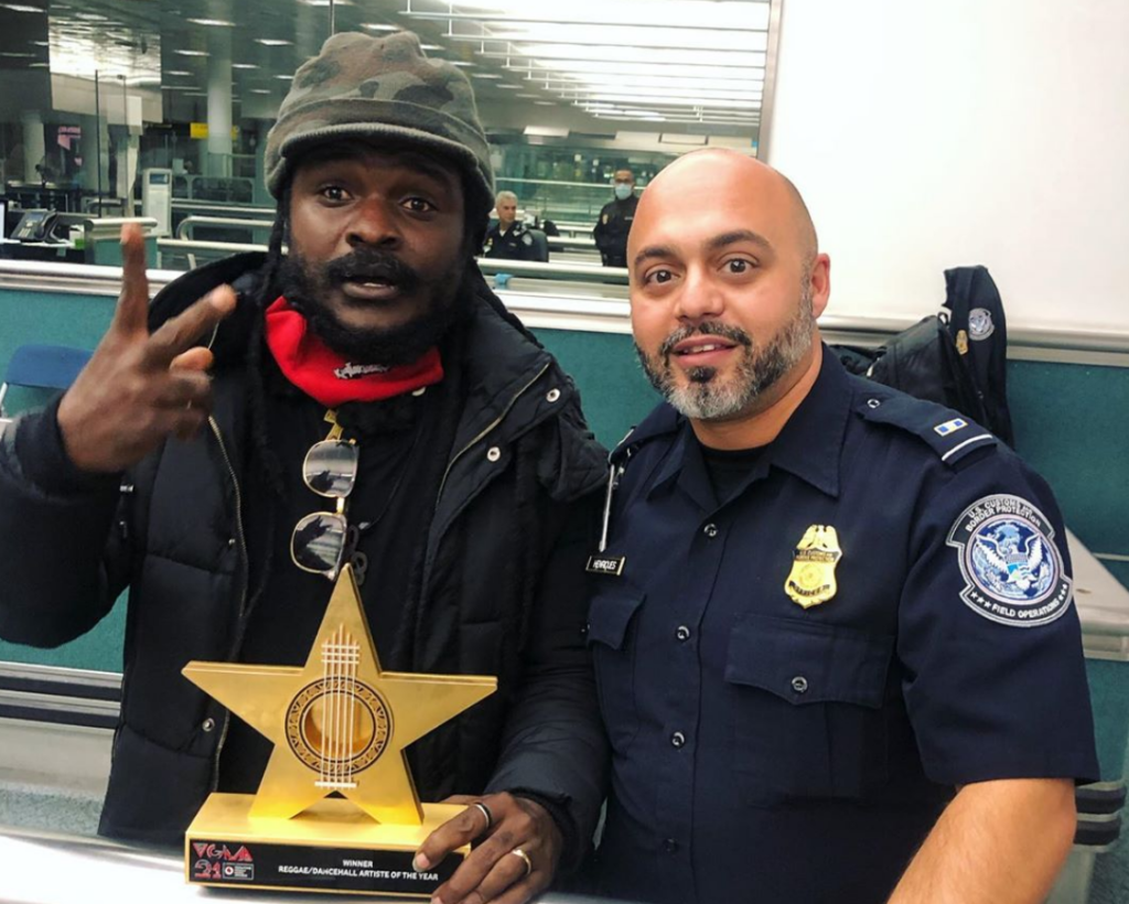 Ras Kuuku presents his VGMA plaque to US Customs official [Photo ...